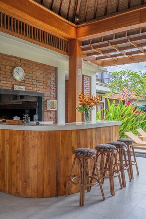 Uma área de bar com balcão de madeira, parede de tijolos, um relógio e um kit de primeiros socorros.
