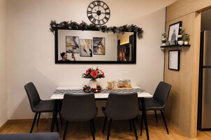 Uma sala de jantar com mesa, cadeiras, um relógio e um espelho decorado com obras de arte.