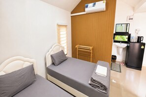 Quarto de hotel compacto com uma cama, uma pequena mesa, pia e geladeira.