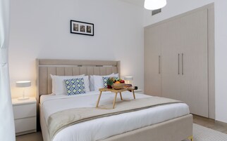 Quarto bem arrumado com uma cama, mesas de cabeceira, abajur, quadro na parede e guarda-roupa.