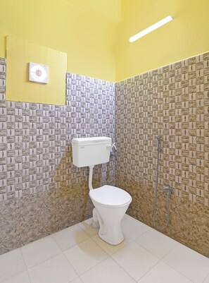 Casa de banho com sanita, chuveiro e aquecedor fixado na parede.