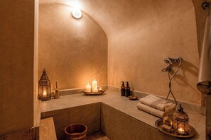 Um quarto de spa com banheira, velas e um candeeiro.