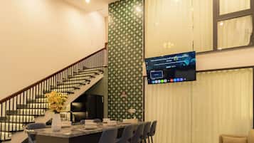 Uma cozinha moderna com ilha central, banquetas, área de refeições com sofá e uma escada.