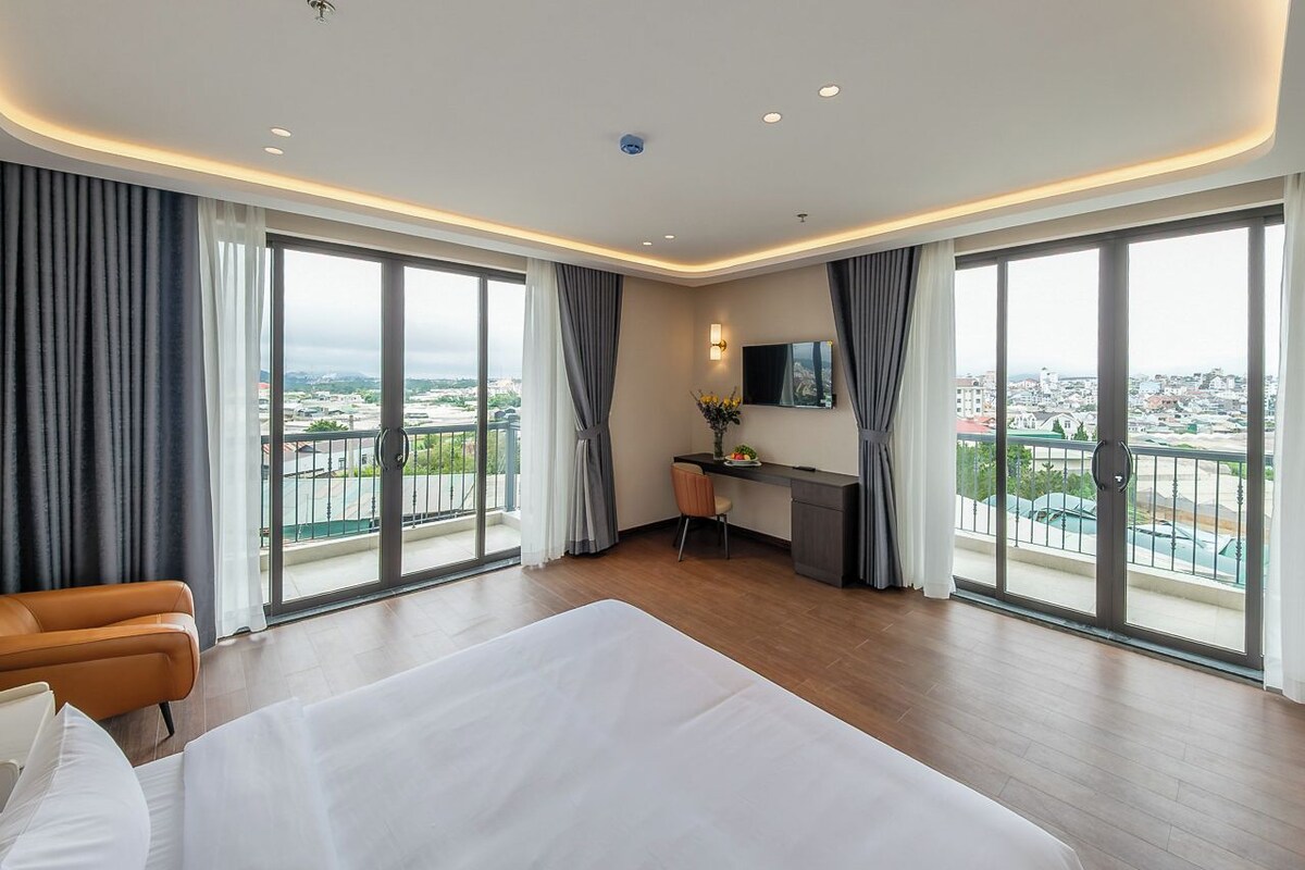 Quarto de hotel com uma cama grande, uma mesa, uma cadeira e uma televisão.