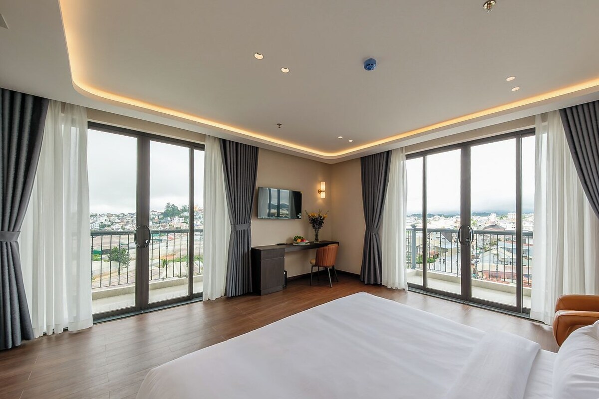 Quarto de hotel com uma cama grande, uma escrivaninha e vista para a cidade.