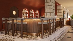 Uma área de bar com balcão de madeira curvo, vários bancos altos e piso estampado.