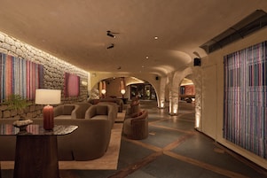 Um hall amplo com parede de pedra, área de estar com sofás e poltronas, e parede decorada com padrão.