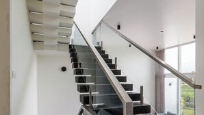 Uma escadaria moderna com corrimãos de vidro e vista para o exterior.