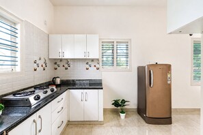 Uma cozinha com armários brancos, bancada preta, fogão de aço inoxidável e geladeira marrom.
