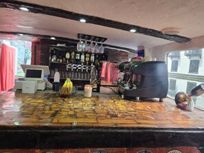 Uma área de bar com máquina de café, computador e diversos frascos em prateleiras.