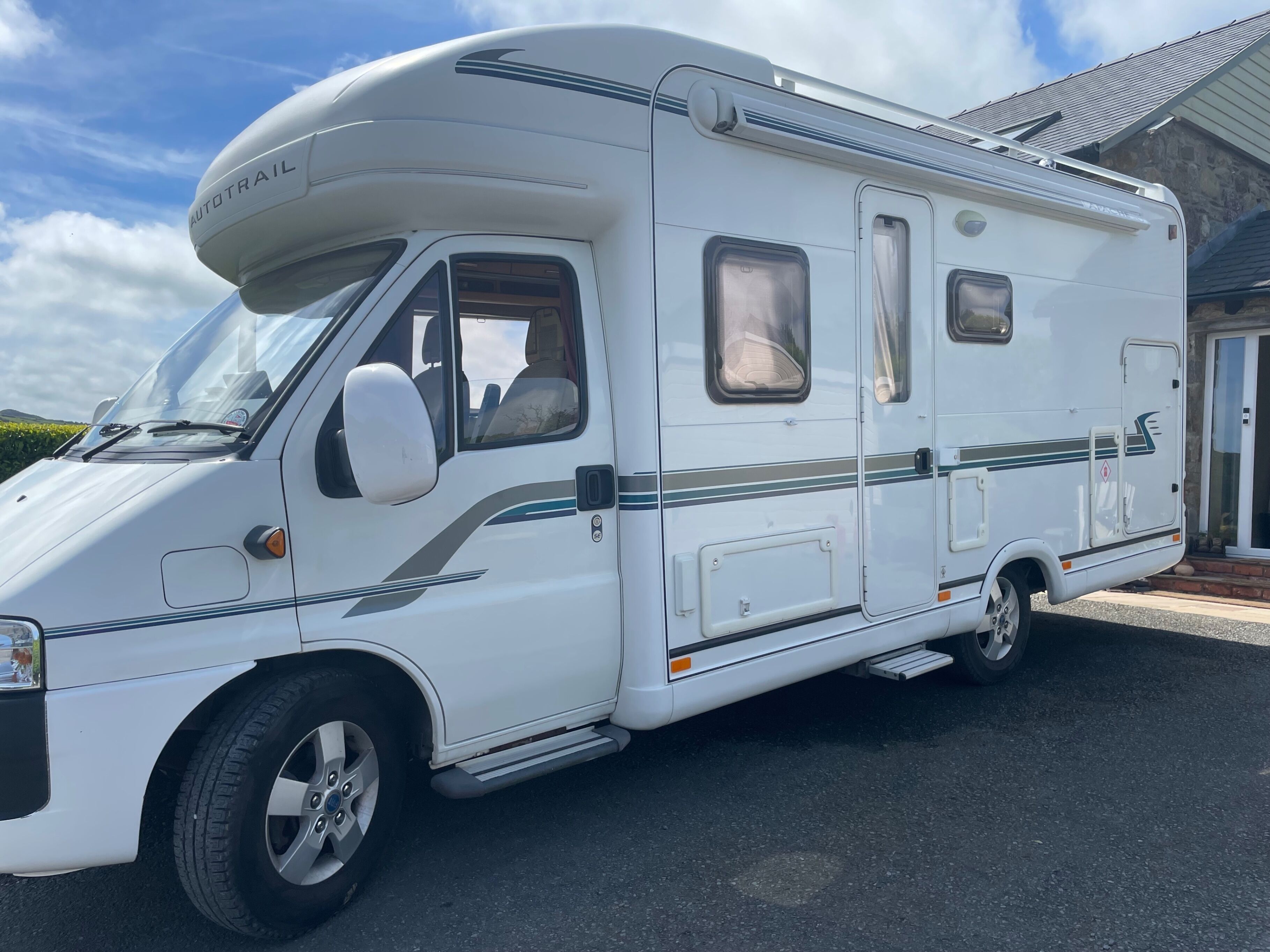 Uma motorhome branca estacionada em frente a um edifício com garagem.