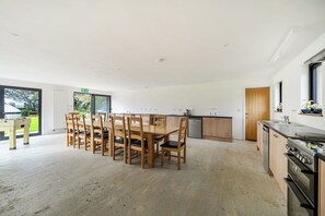Cozinha ampla com armários de madeira, mesa de jantar com cadeiras e uma grande janela.