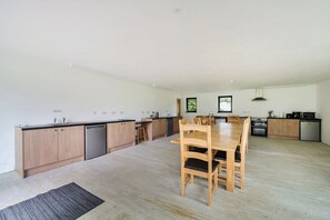Cozinha moderna com armários de madeira, ilha central e mesa de jantar com cadeiras.