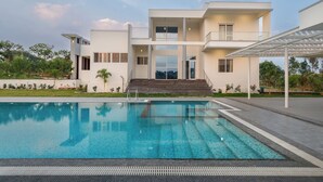 Uma casa moderna de dois andares com uma piscina na frente.