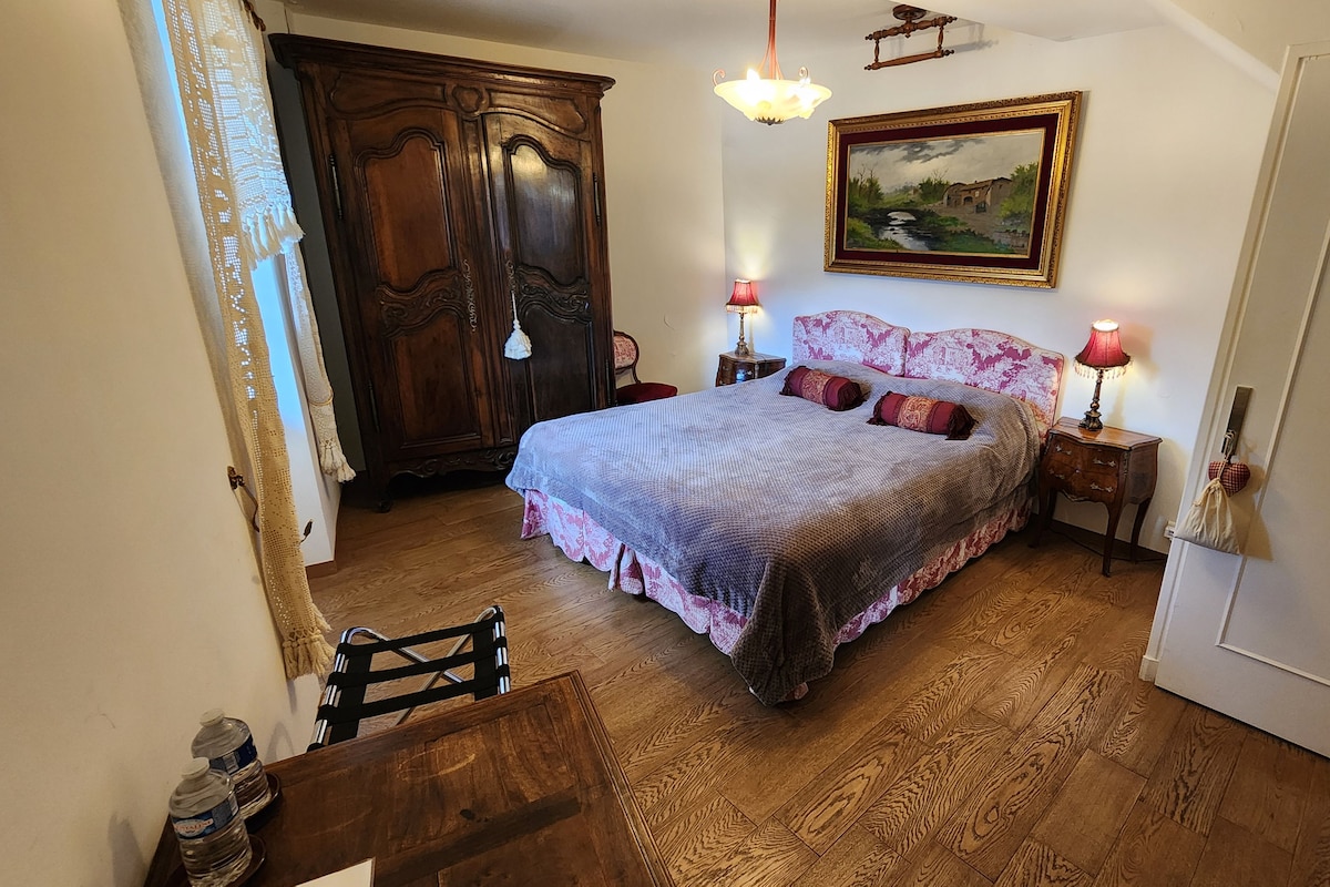 Quarto com uma cama grande, guarda-roupa de madeira e um quadro na parede.