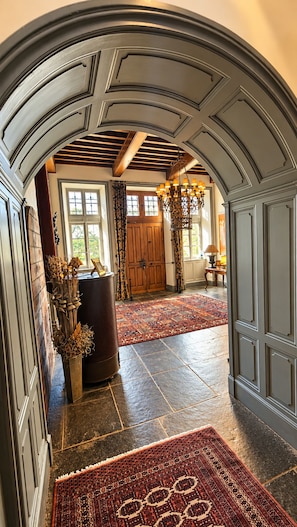 Um corredor com tapete estampado, porta de madeira e lustre.