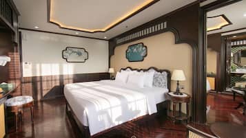 Quarto de hotel com uma cama grande, mesa de cabeceira, abajur e espelho.