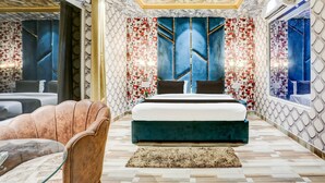 Quarto moderno com uma cama grande, área de estar com uma poltrona e paredes estampadas.