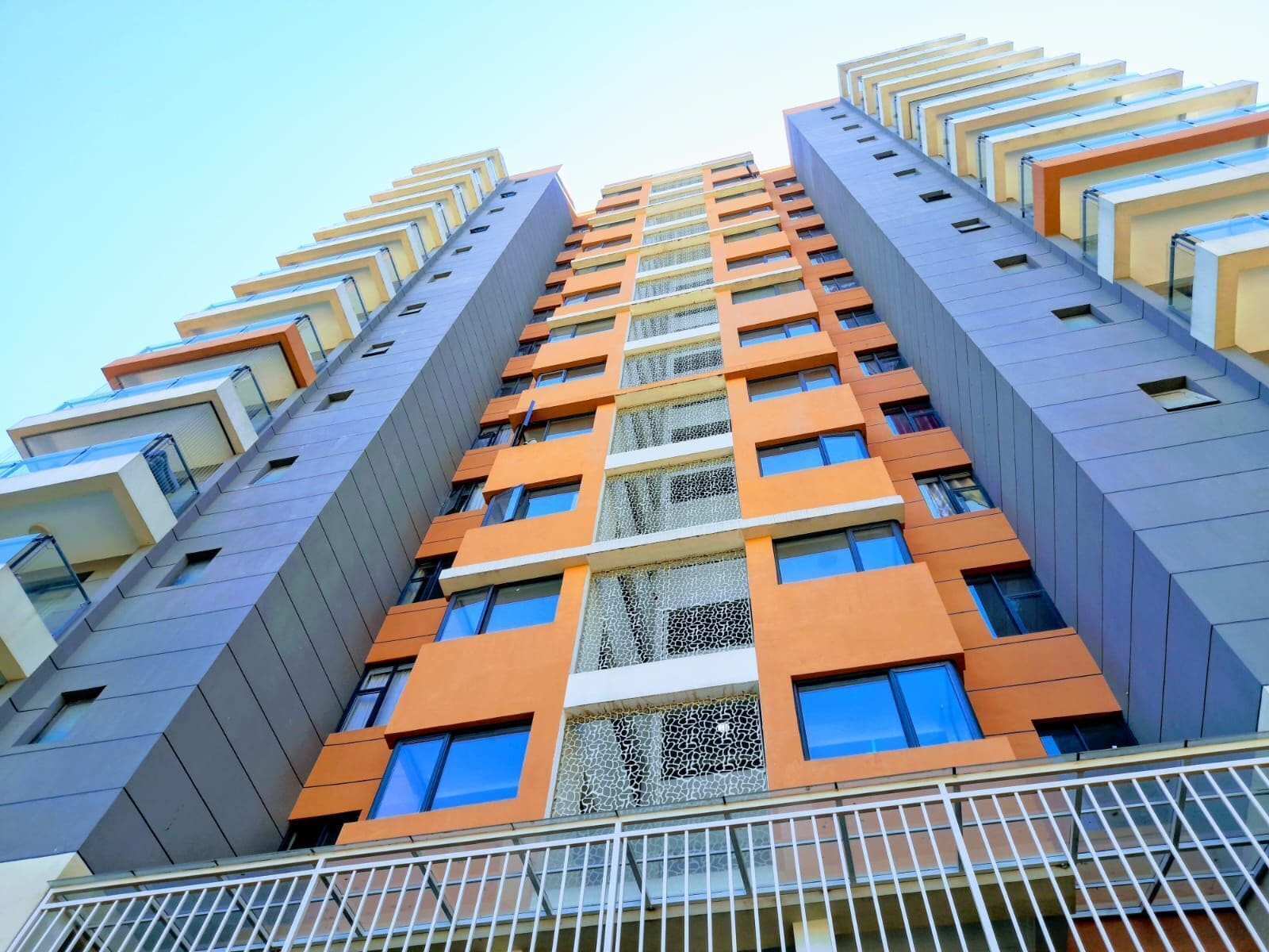 Um edifício alto com várias varandas e design arquitetônico moderno.