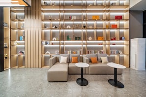 Uma sala de estar moderna com um sofá seccional, duas mesinhas e uma estante embutida com diversos objetos decorativos.