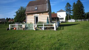 Uma casa térrea de tijolos com telhado de telhas, cerca branca e gramado.