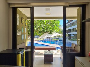 Quarto com vista para uma piscina, mobiliário exterior e área de refeições.