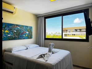 Quarto de hotel com cama, um quadro, janela com vista e ar condicionado.
