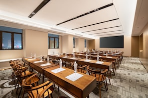 Uma sala de conferência com várias mesas, cadeiras e uma tela grande para apresentações.