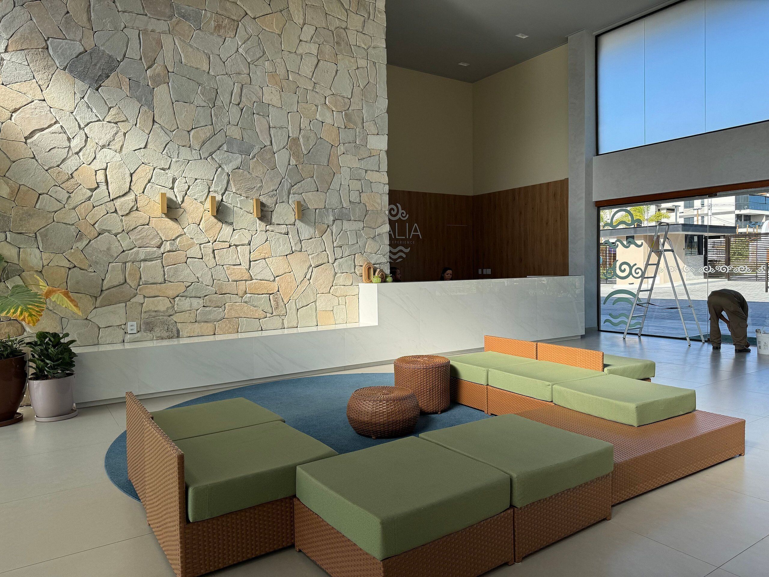 Um lobby moderno com parede de pedra, área de estar e balcão de recepção.