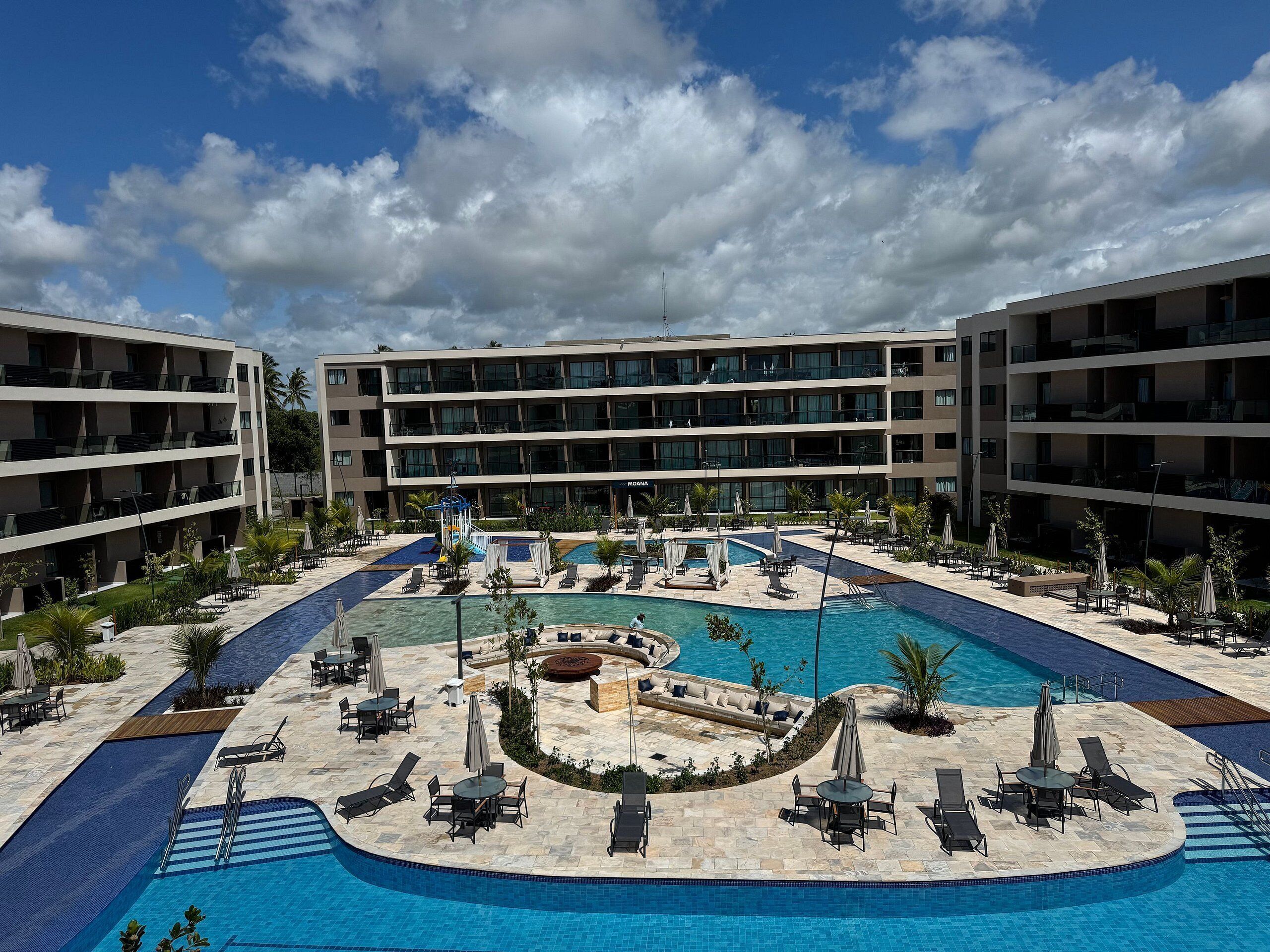 Um hotel com piscina central, várias varandas e áreas de estar ao ar livre.