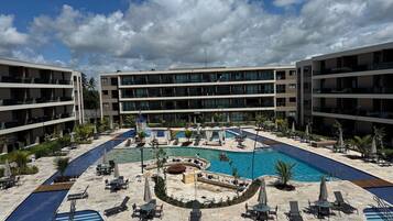 Um hotel com piscina central, várias varandas e áreas de estar ao ar livre.