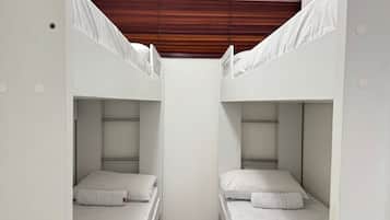 Quarto com beliches, roupa de cama branca e teto de madeira.