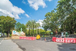 Uma entrada com portão para um parque, céu claro e árvores.