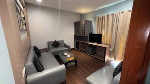 Uma sala de estar moderna com um sofá, uma mesa de centro, uma televisão de tela plana e um armário.