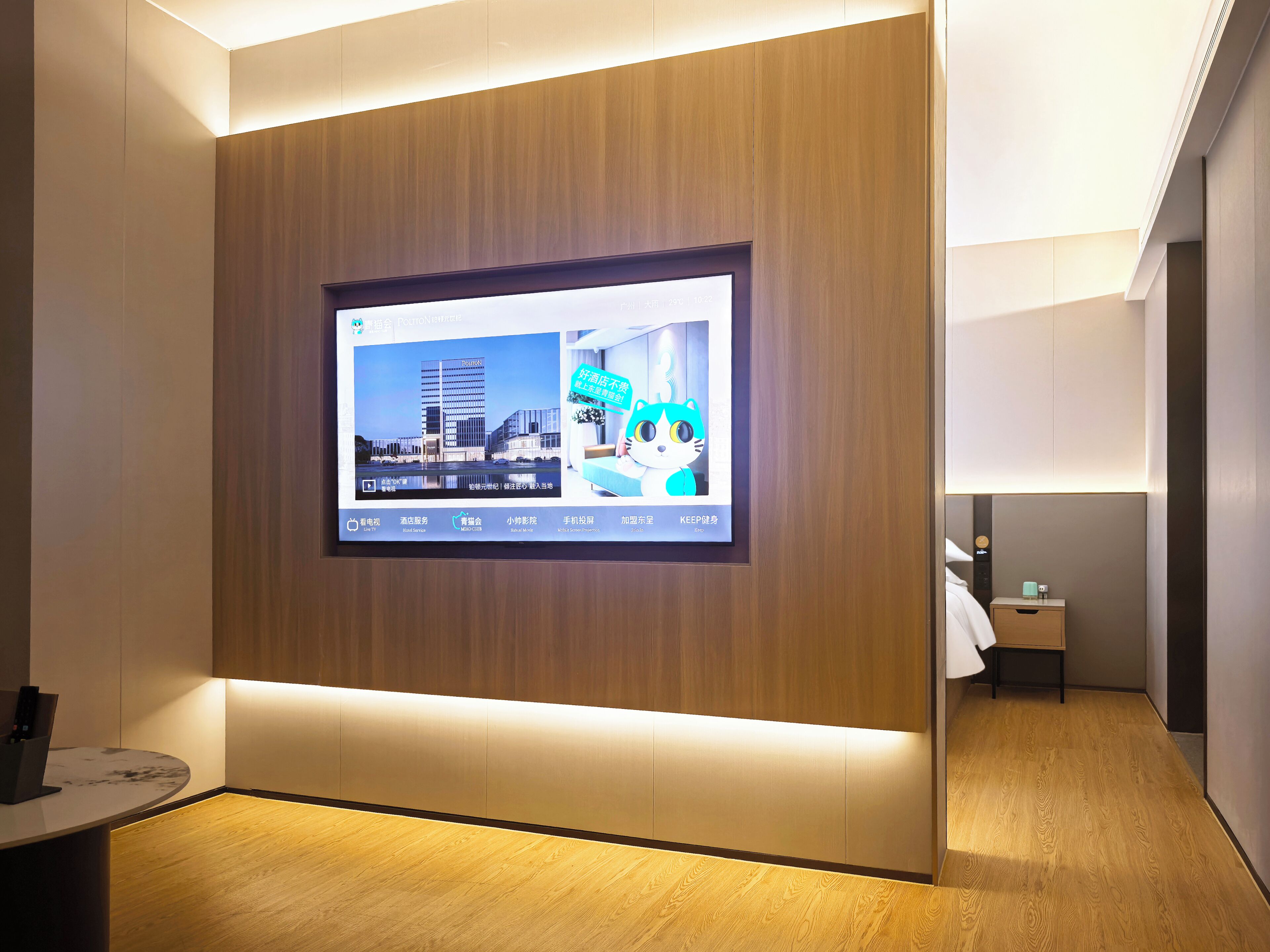 Um lobby de hotel com uma tela digital grande exibindo uma paisagem urbana e um personagem de desenho animado.
