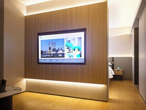 Um lobby de hotel com uma tela digital grande exibindo uma paisagem urbana e um personagem de desenho animado.