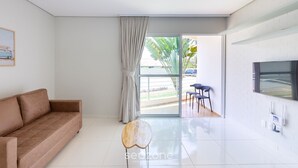 Uma sala de estar moderna com um sofá, uma mesa de centro de madeira e uma TV fixada na parede.