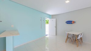 Um interior moderno com uma parede azul clara, uma porta branca e uma área de refeições com mesa e cadeiras brancas.
