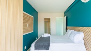 Quarto com cama, mesa de cabeceira, guarda-roupa e porta para outro cômodo.