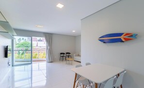 Um interior moderno com área de refeições, um sofá e vista através de uma porta de vidro.