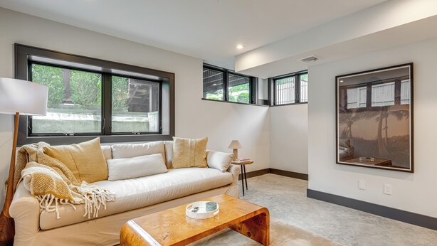 Uma sala de estar moderna com sofá, mesa de centro e grandes janelas.