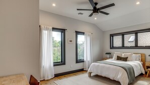 Quarto com cama, mesa de cabeceira, abajur e ventilador de teto.
