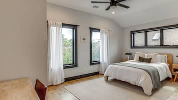 Quarto com cama, mesa de cabeceira, abajur e ventilador de teto.