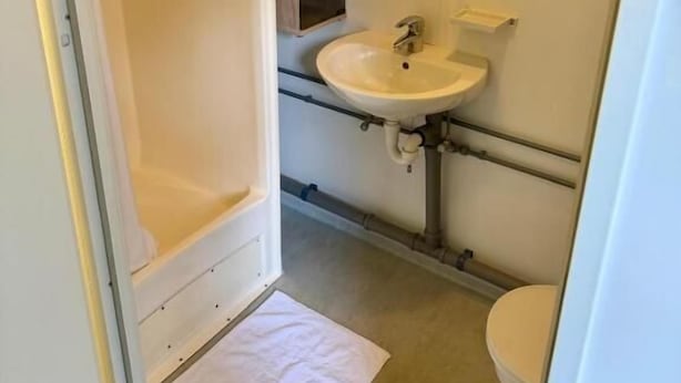 A bathroom with a sink, toilet, and open shower door.