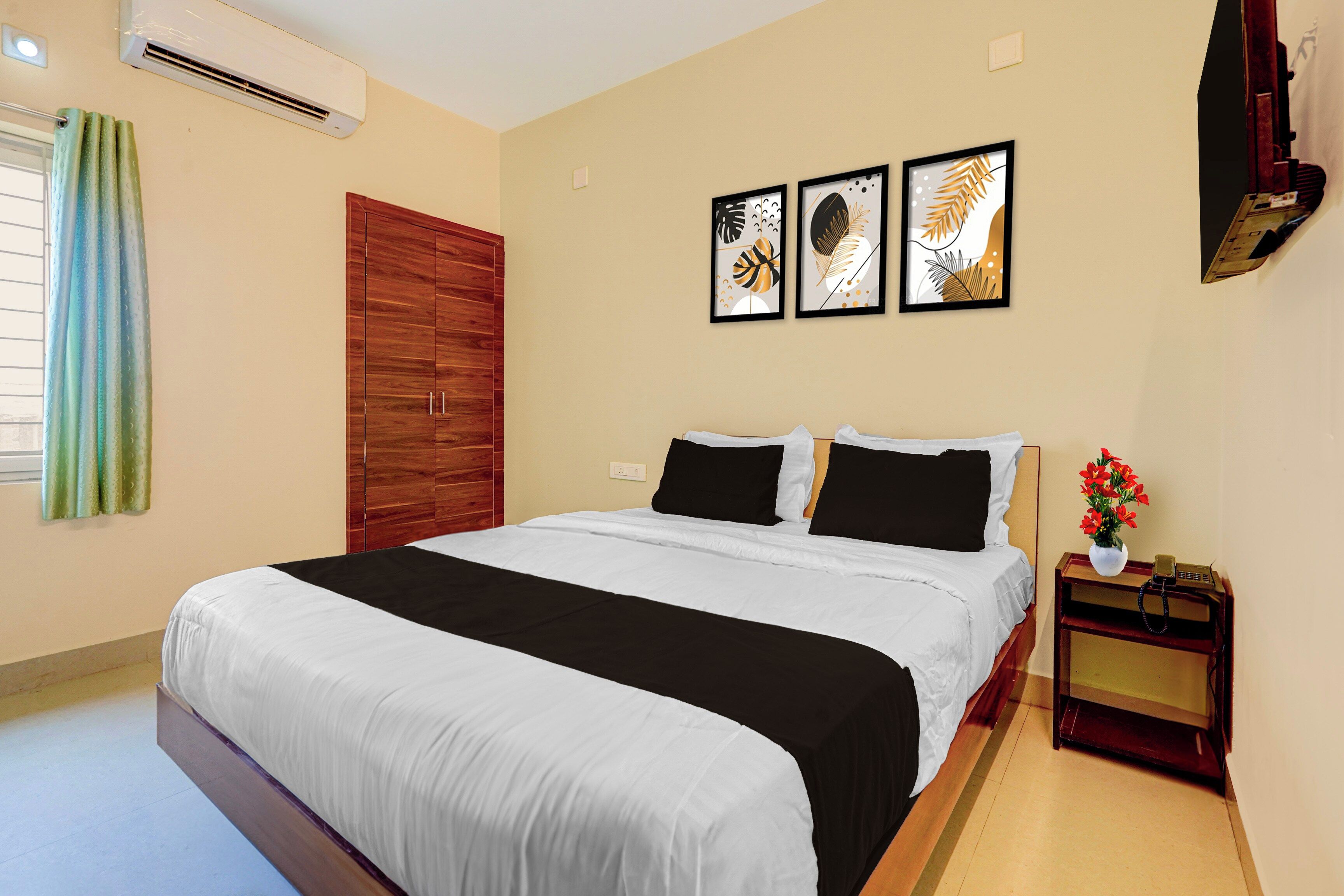 Quarto de hotel com cama, mesa de cabeceira, telefone e ar condicionado fixado na parede.