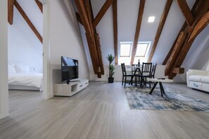 Quarto moderno estilo loft com cama grande, televisão e área de jantar com cadeiras e mesa.