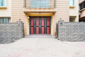 Entrada de edifício com portas duplas, fachada de pedra e portão de metal.