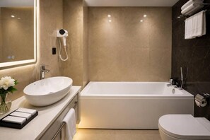 Uma casa de banho moderna com uma banheira grande, uma pia redonda e um secador de cabelo fixado na parede.