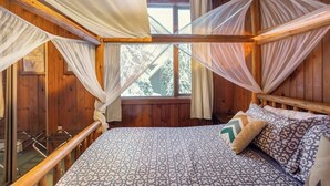 Quarto com cama, paredes de madeira, uma janela e um dossel.