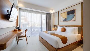 Quarto de hotel moderno com uma cama grande, uma escrivaninha e uma TV fixada na parede.